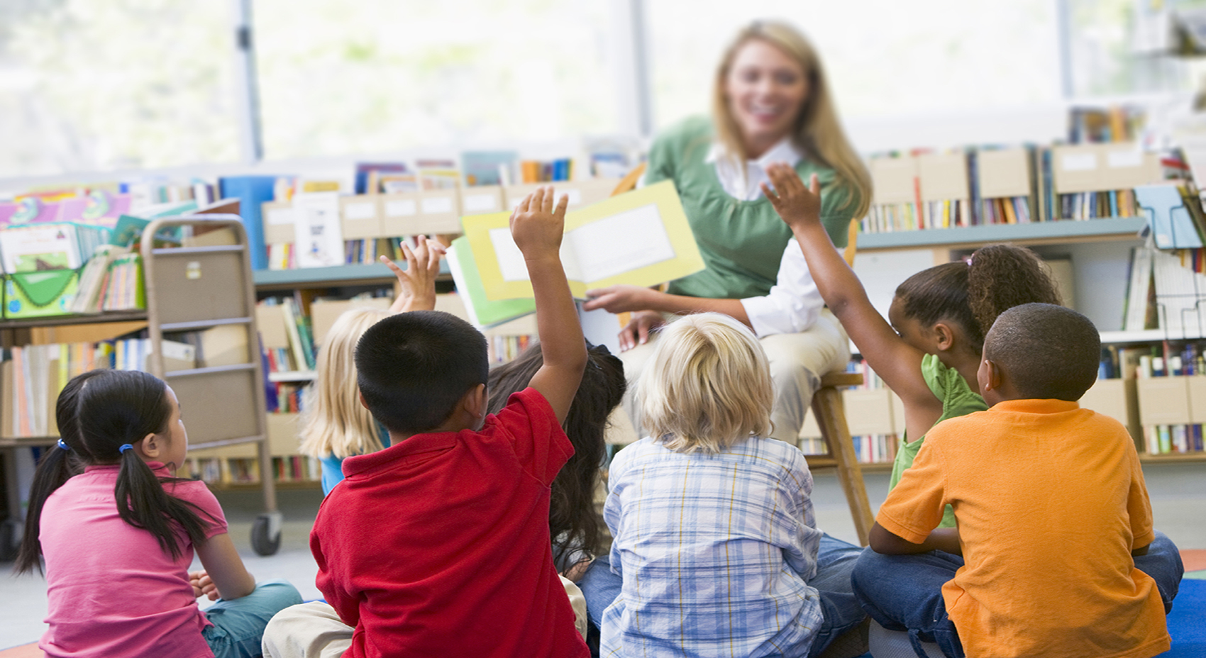 Kindergarten teacher reading to children in library slider | Eckert Seamans